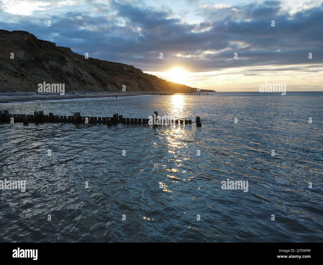 Sunset on coast with shining sun illuminating the undulating sea with ...
