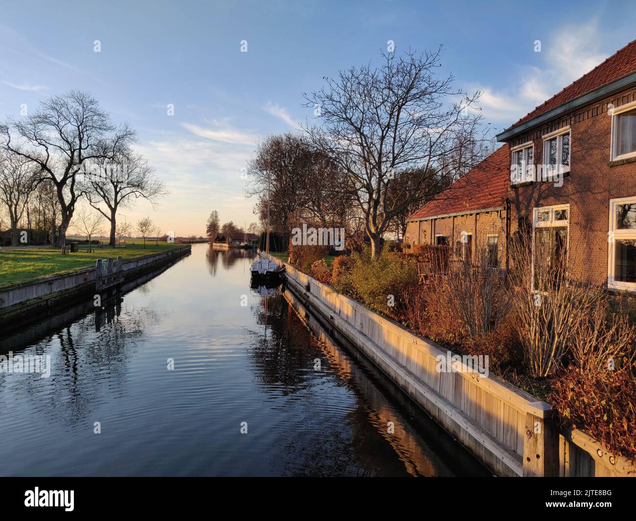 A narrow water canal surrounded by trees and houses Stock Photo - Alamy