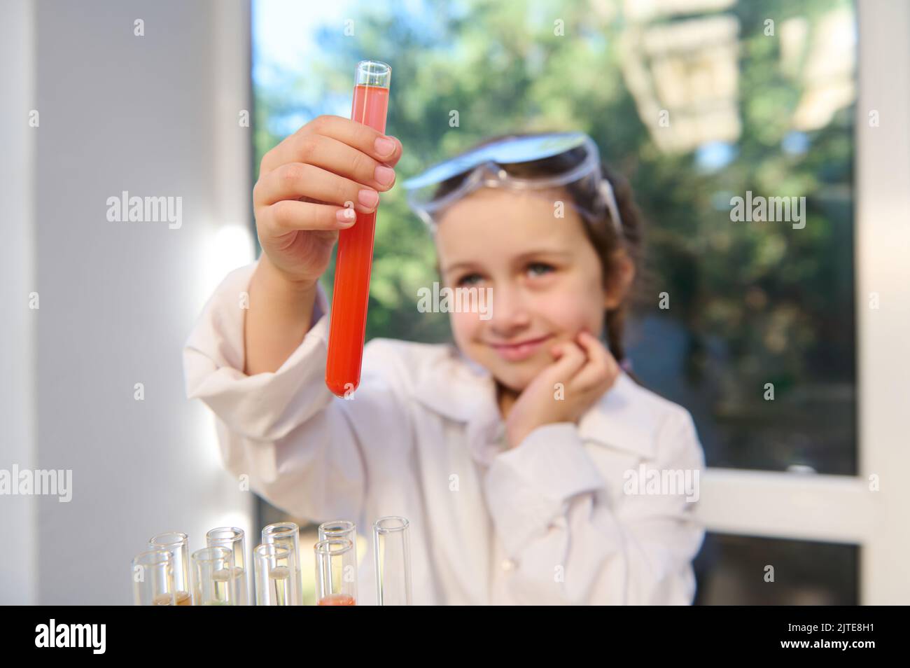 Details: hands of a little chemist observing a test tube with going ...