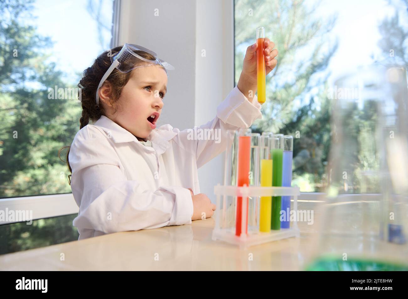 Delighted schoolgirl observes a chemical reaction going in a test tube ...