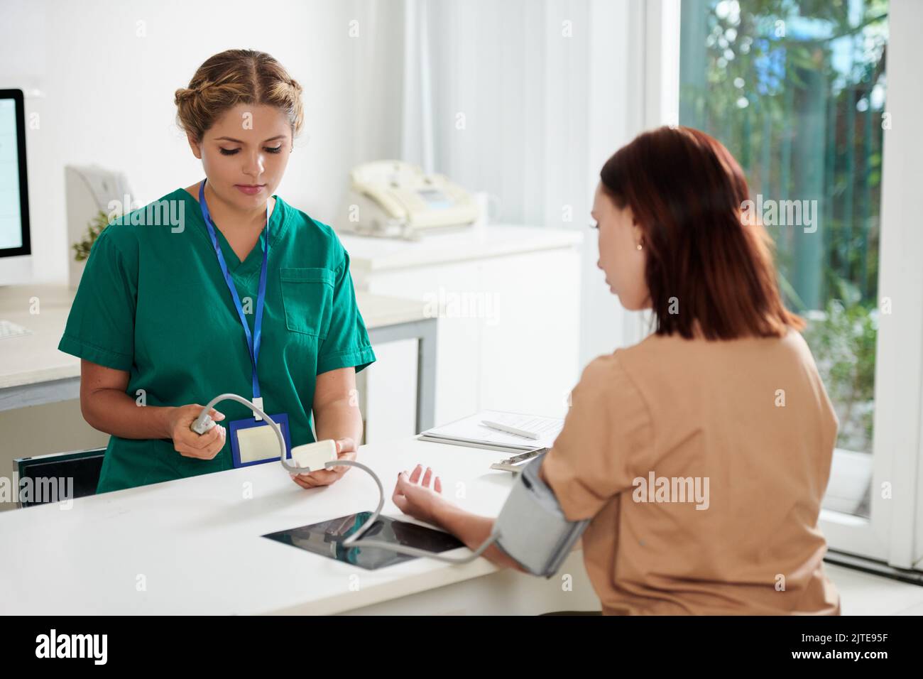 Medical nurse measuring blood pressure of female patient Stock Photo ...