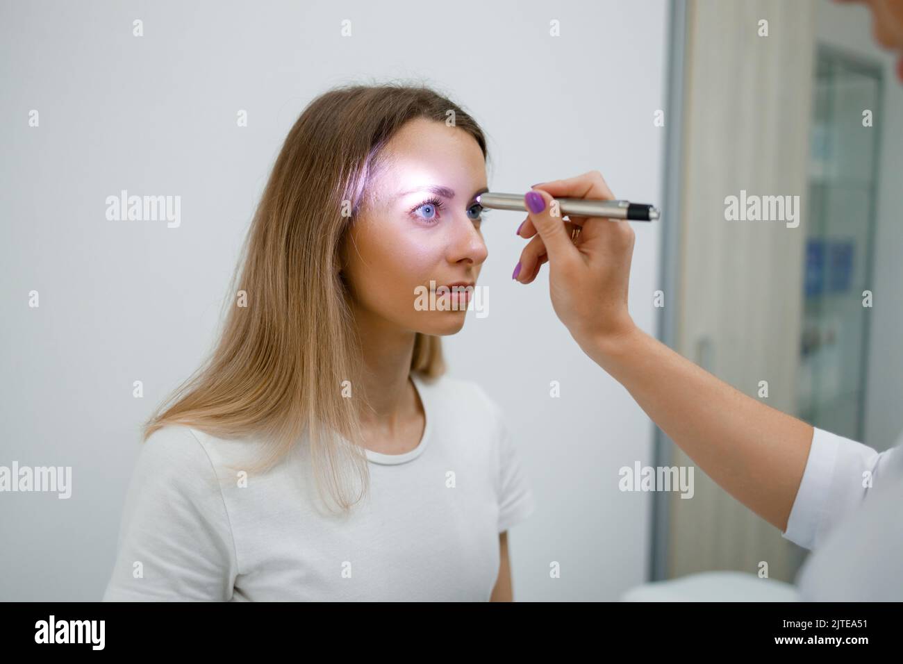 Neurologist doctor checking pupillary response to light with flashlight ...