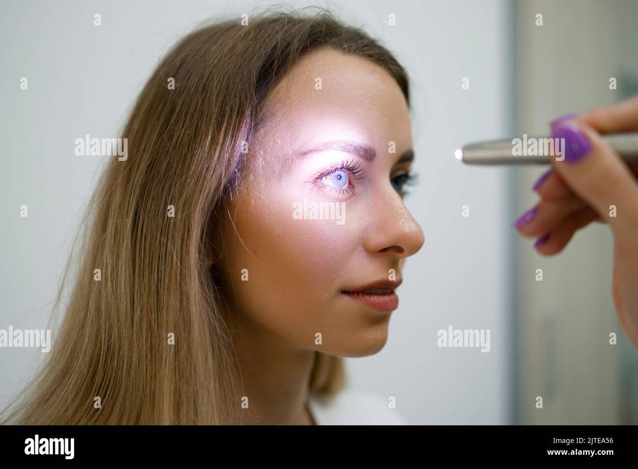 Close up view of doctor testing reflexes of the eye of young woman ...