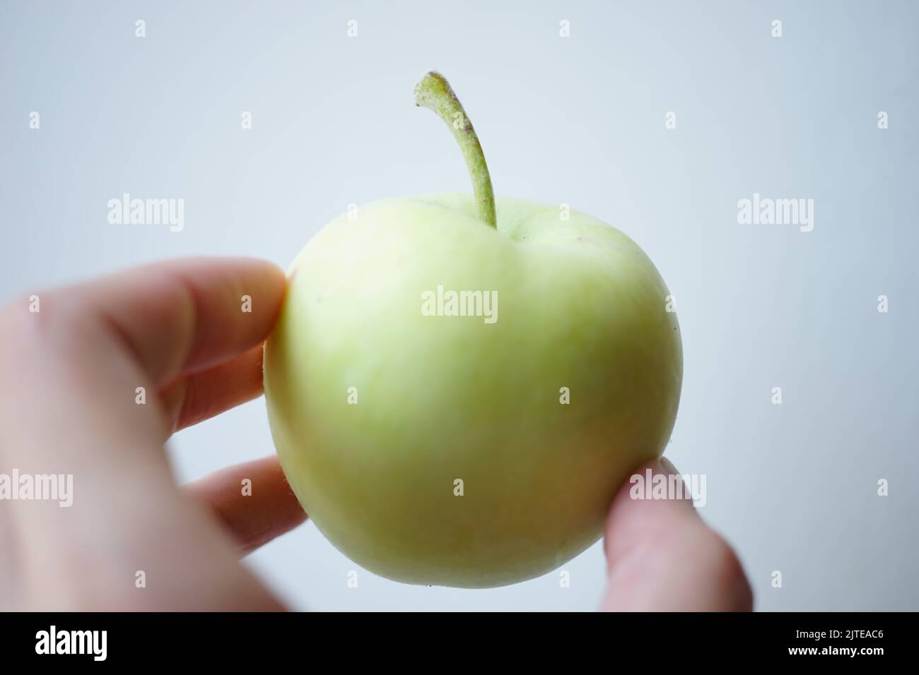 Green apple in female fingers on white background Stock Photo - Alamy