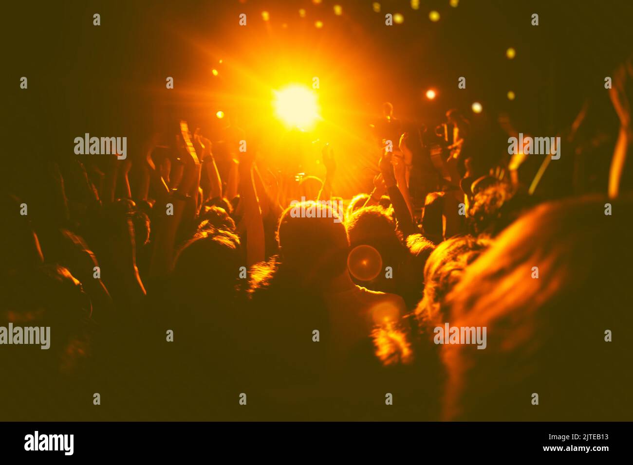 A crowded concert hall with scene stage orange and yellow lights, rock ...