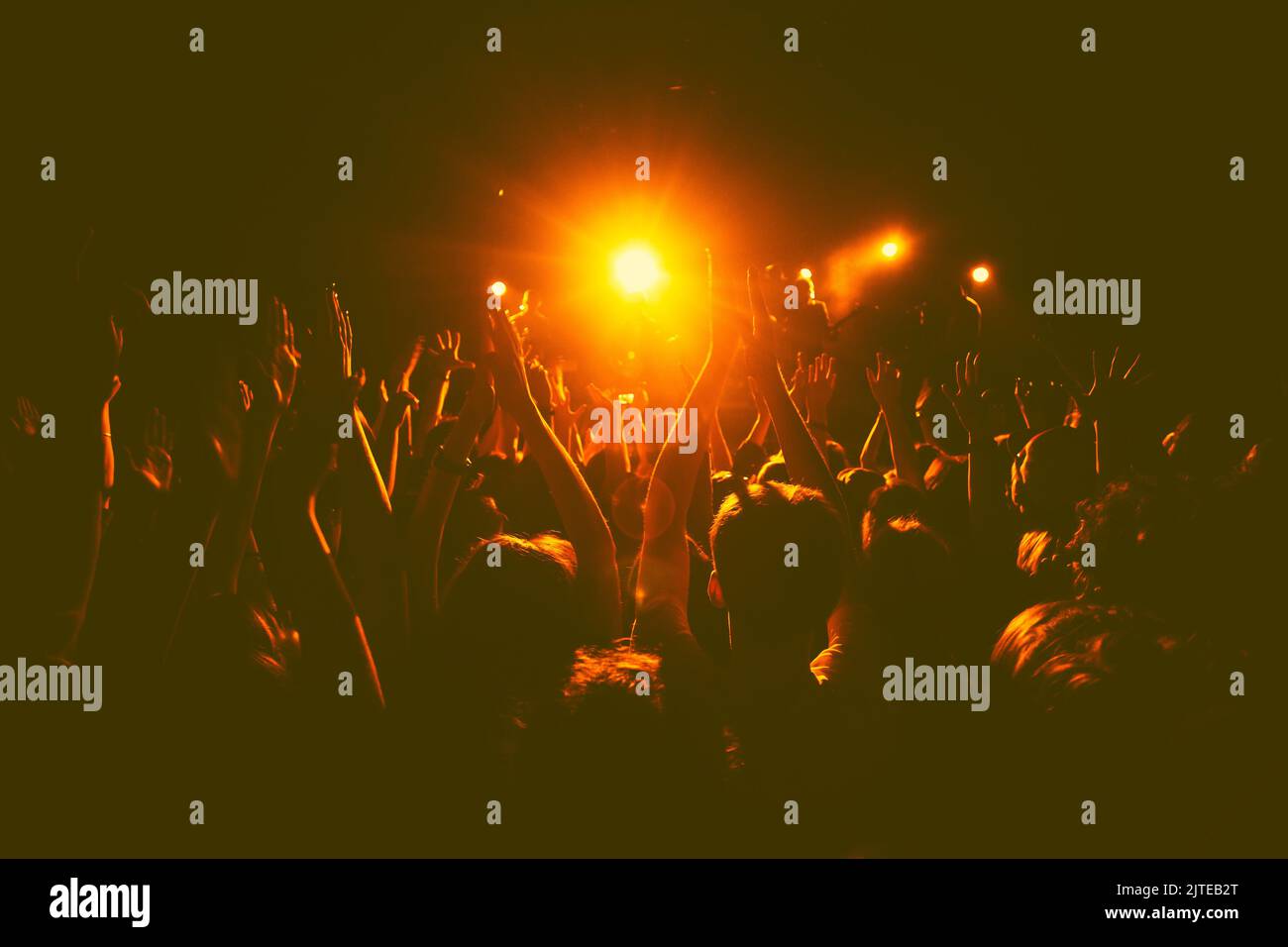 A crowded concert hall with scene stage orange and yellow lights, rock ...