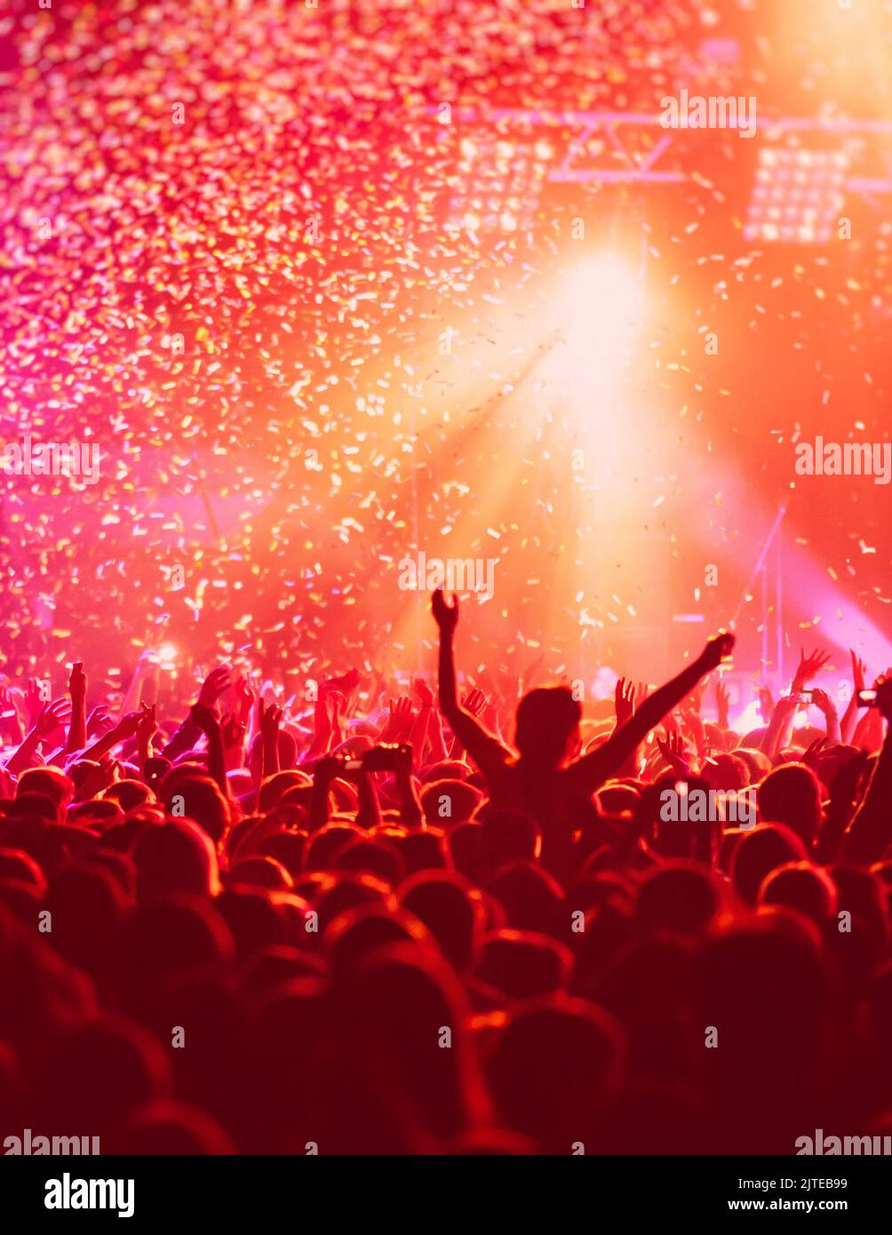 A crowded concert hall with scene stage in red lights, rock show ...