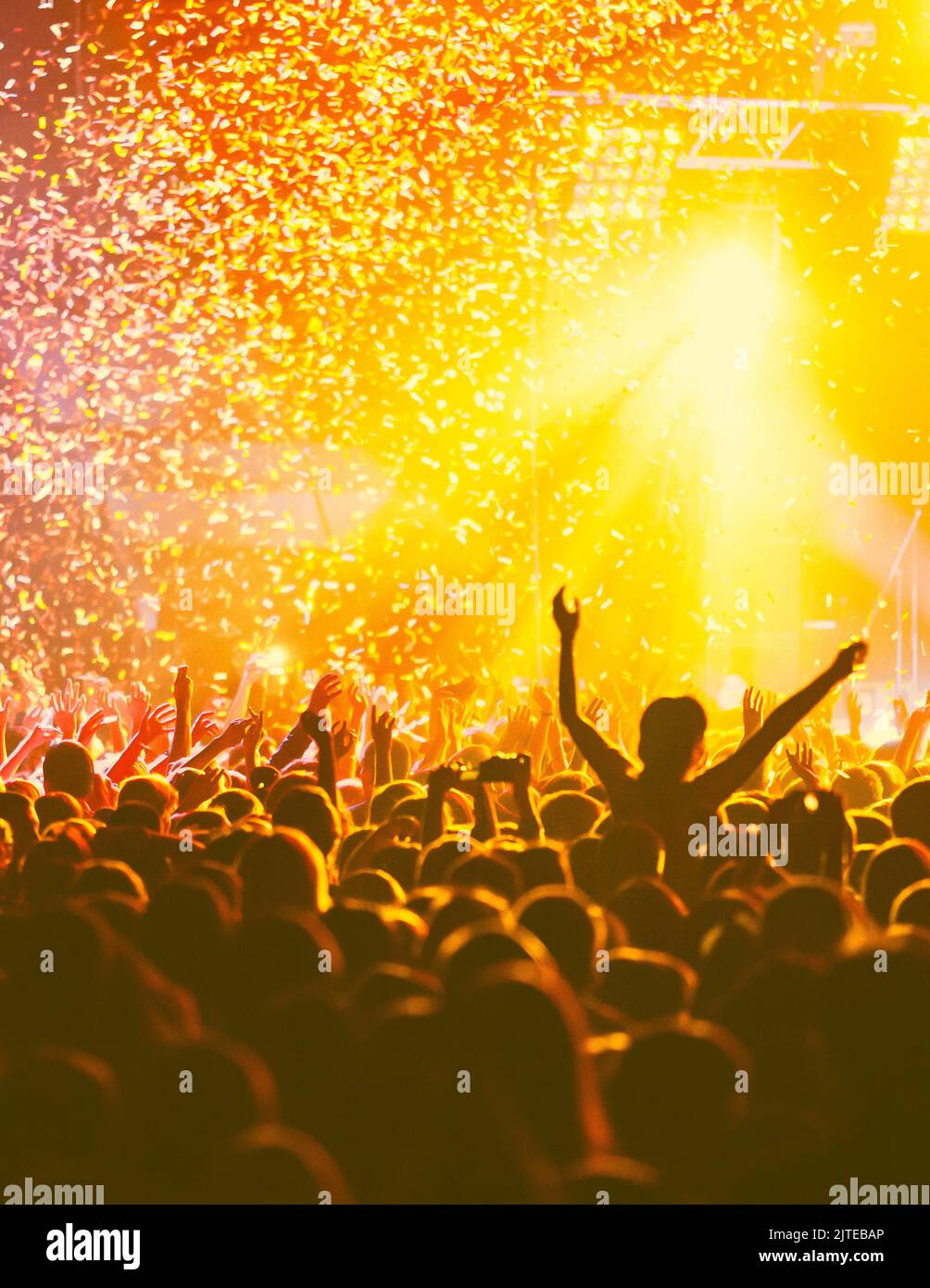 A crowded concert hall with scene stage orange and yellow lights, rock ...