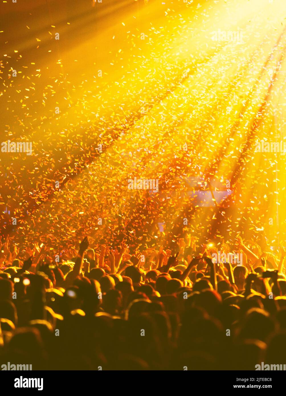 A crowded concert hall with scene stage orange and yellow lights, rock ...