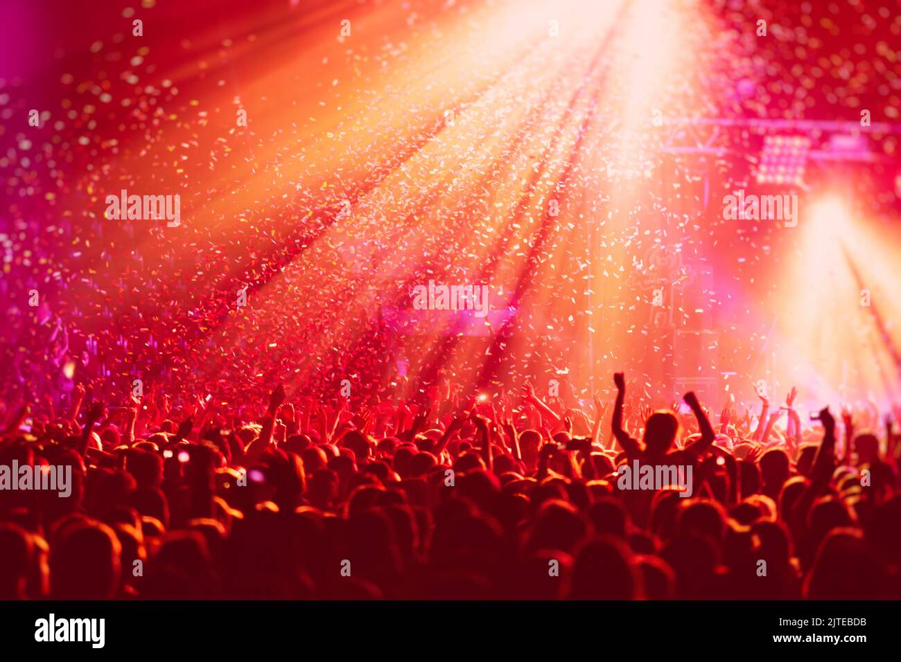 A crowded concert hall with scene stage in red lights, rock show ...