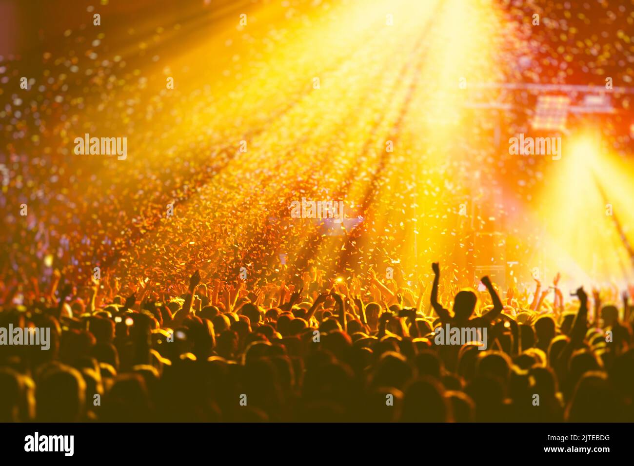 A crowded concert hall with scene stage orange and yellow lights, rock ...
