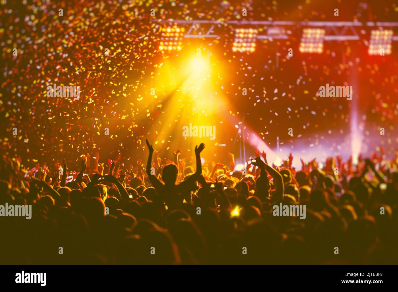 A crowded concert hall with scene stage orange and yellow lights, rock ...