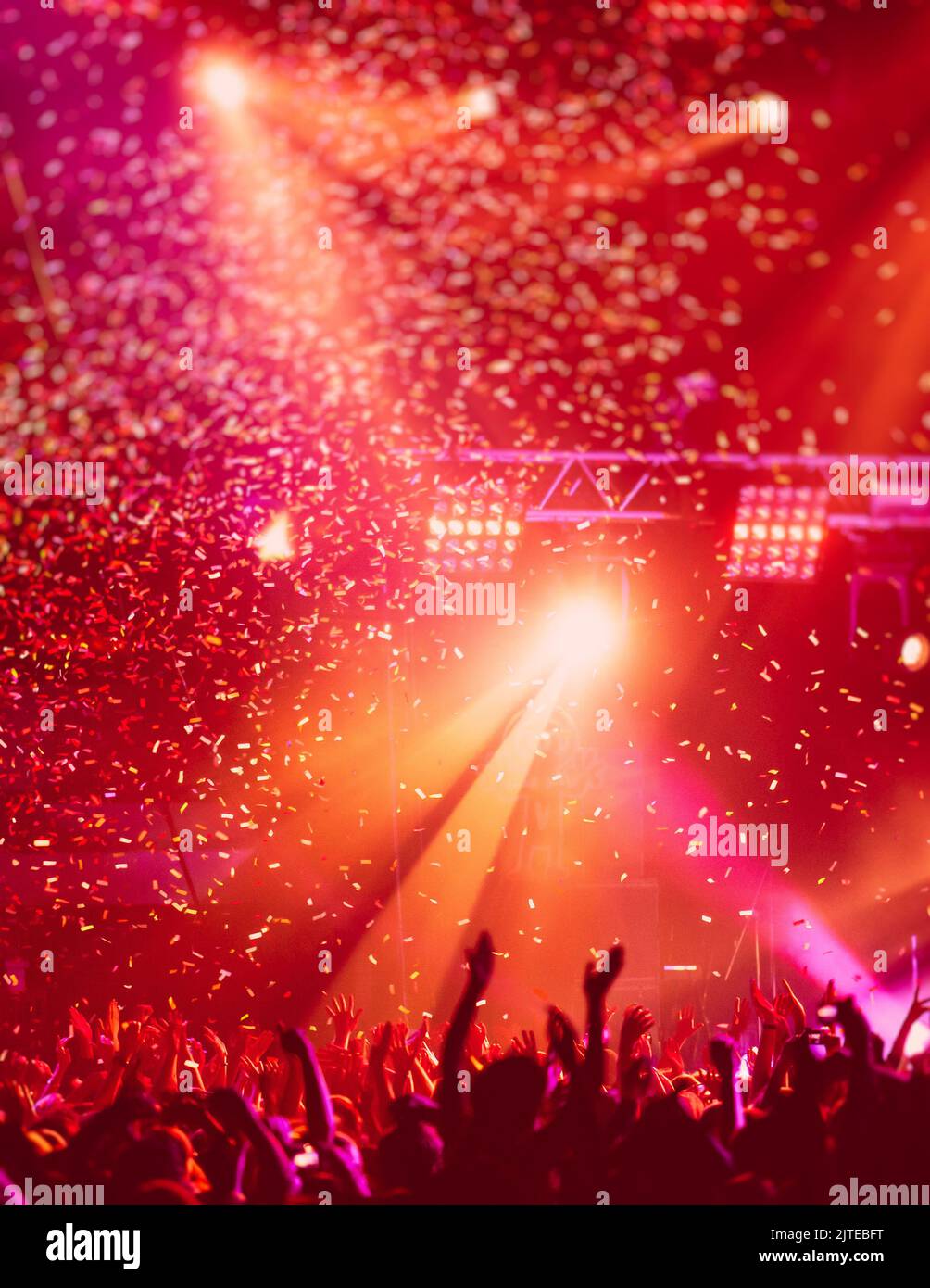 A crowded concert hall with scene stage in red lights, rock show ...