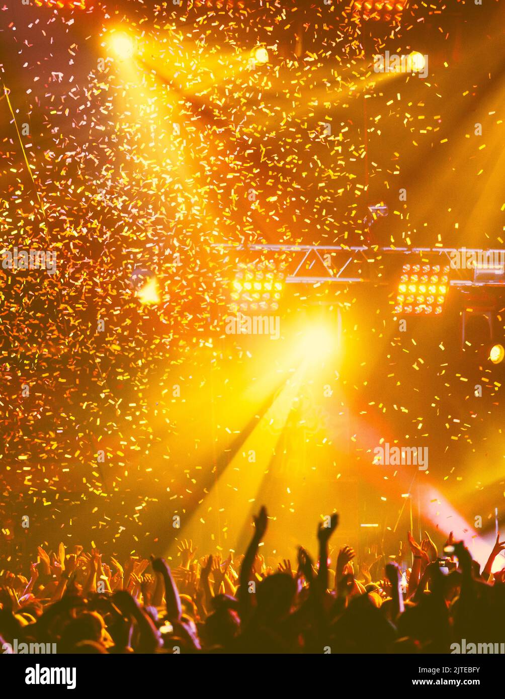 A crowded concert hall with scene stage orange and yellow lights, rock ...