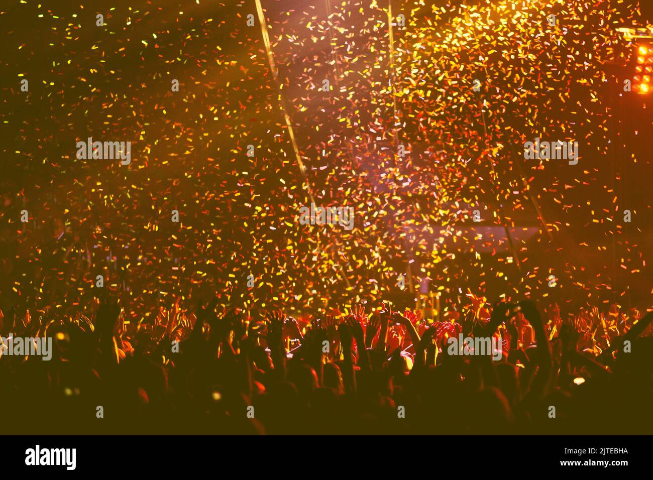 A crowded concert hall with scene stage orange and yellow lights, rock ...