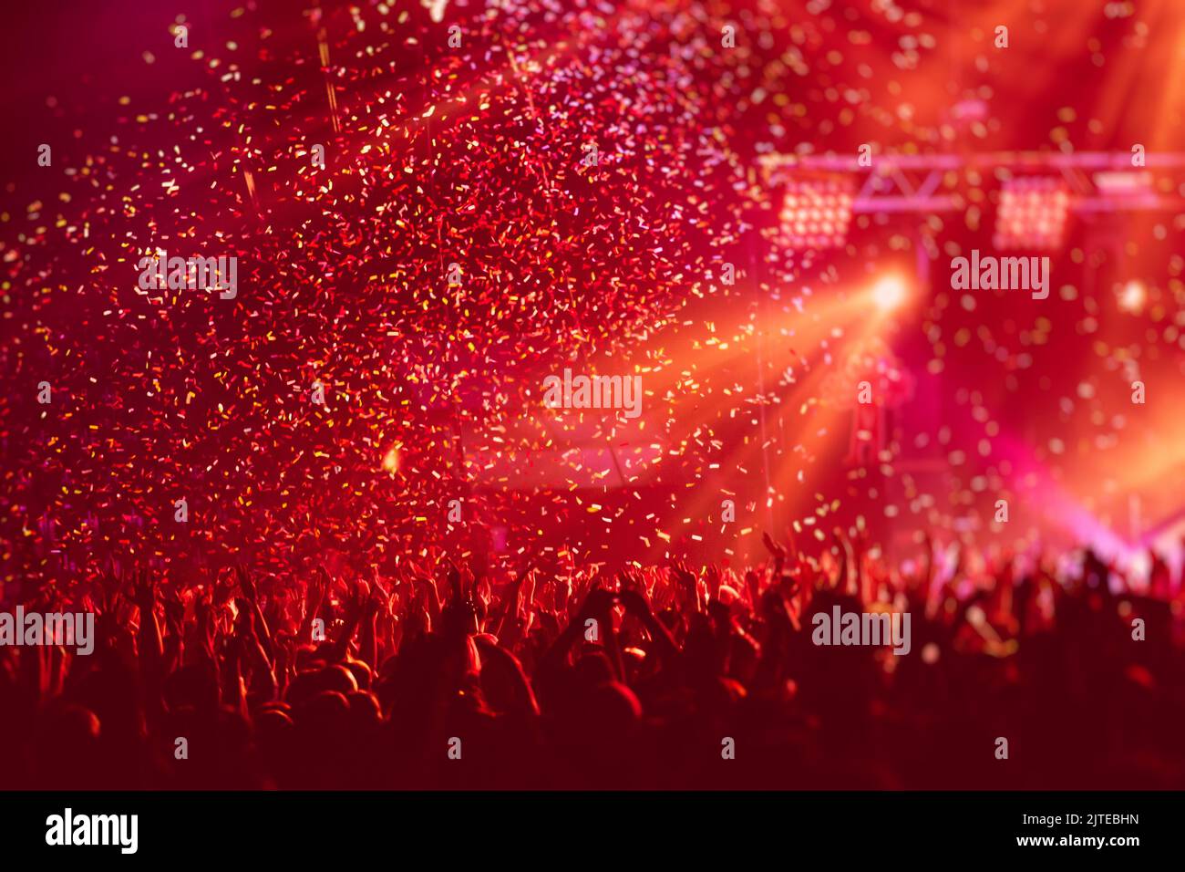A crowded concert hall with scene stage in red lights, rock show ...