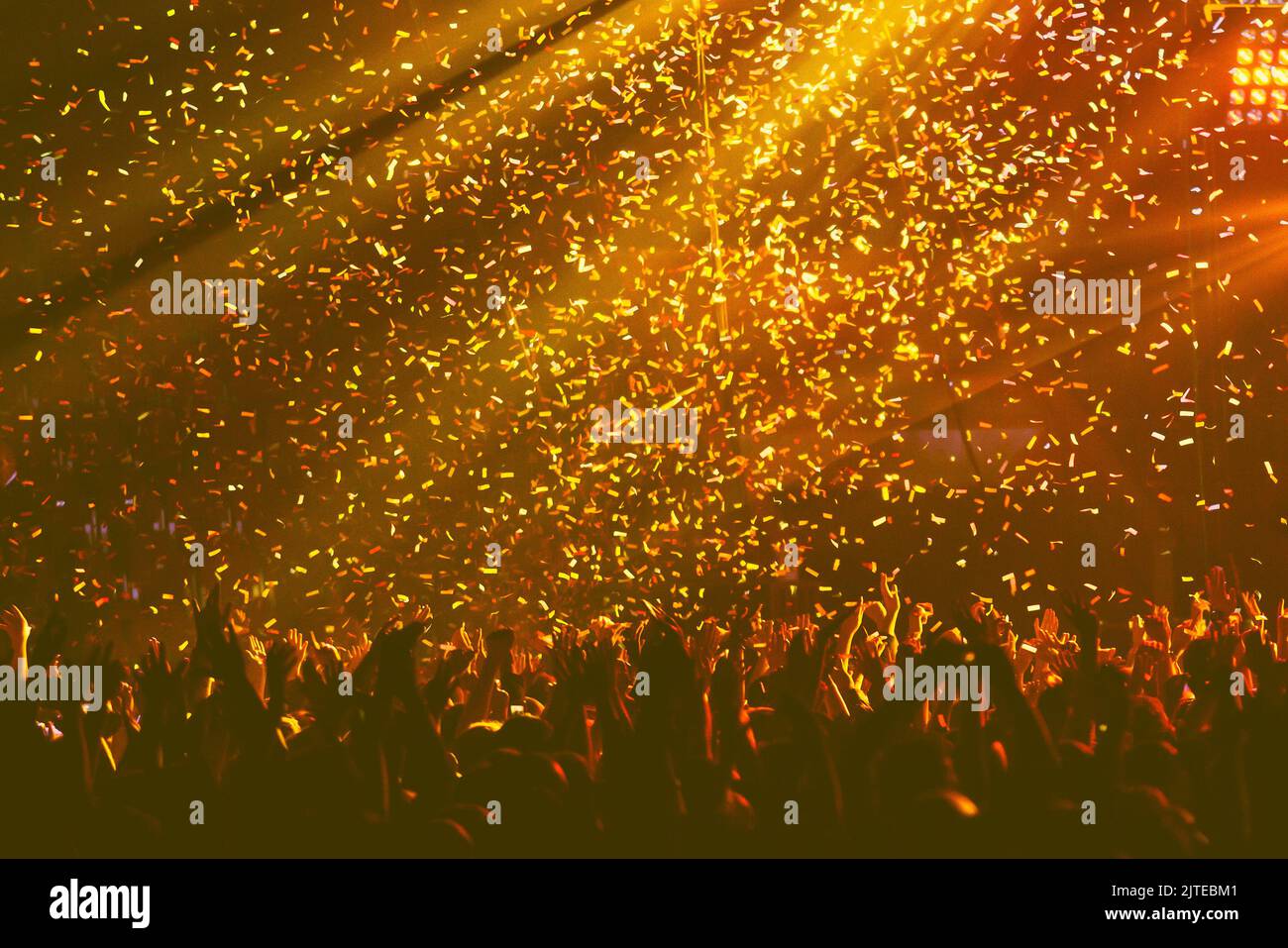 A crowded concert hall with scene stage orange and yellow lights, rock ...