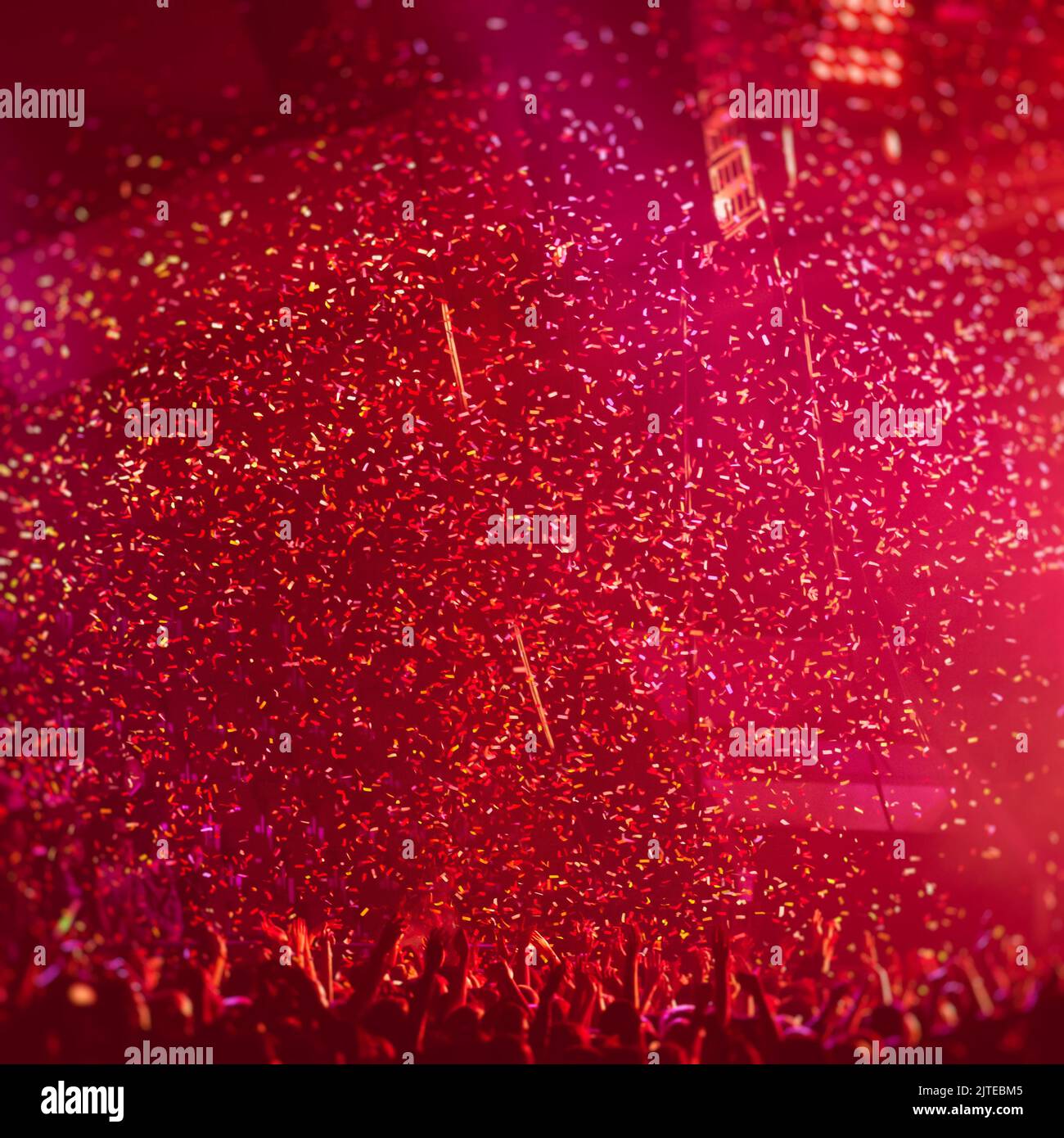 A crowded concert hall with scene stage in red lights, rock show ...