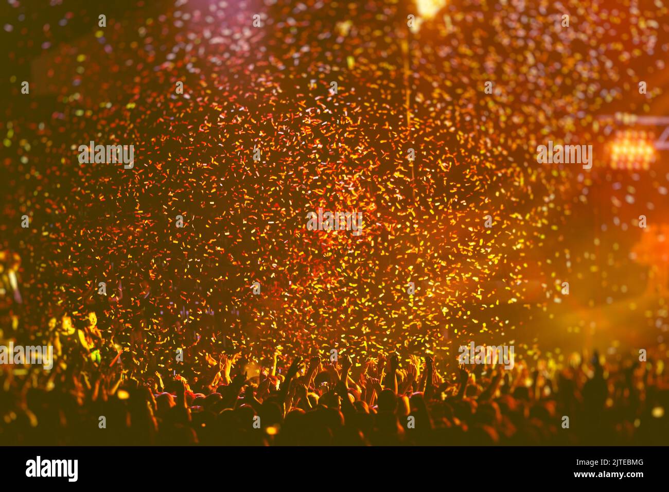 A crowded concert hall with scene stage orange and yellow lights, rock ...