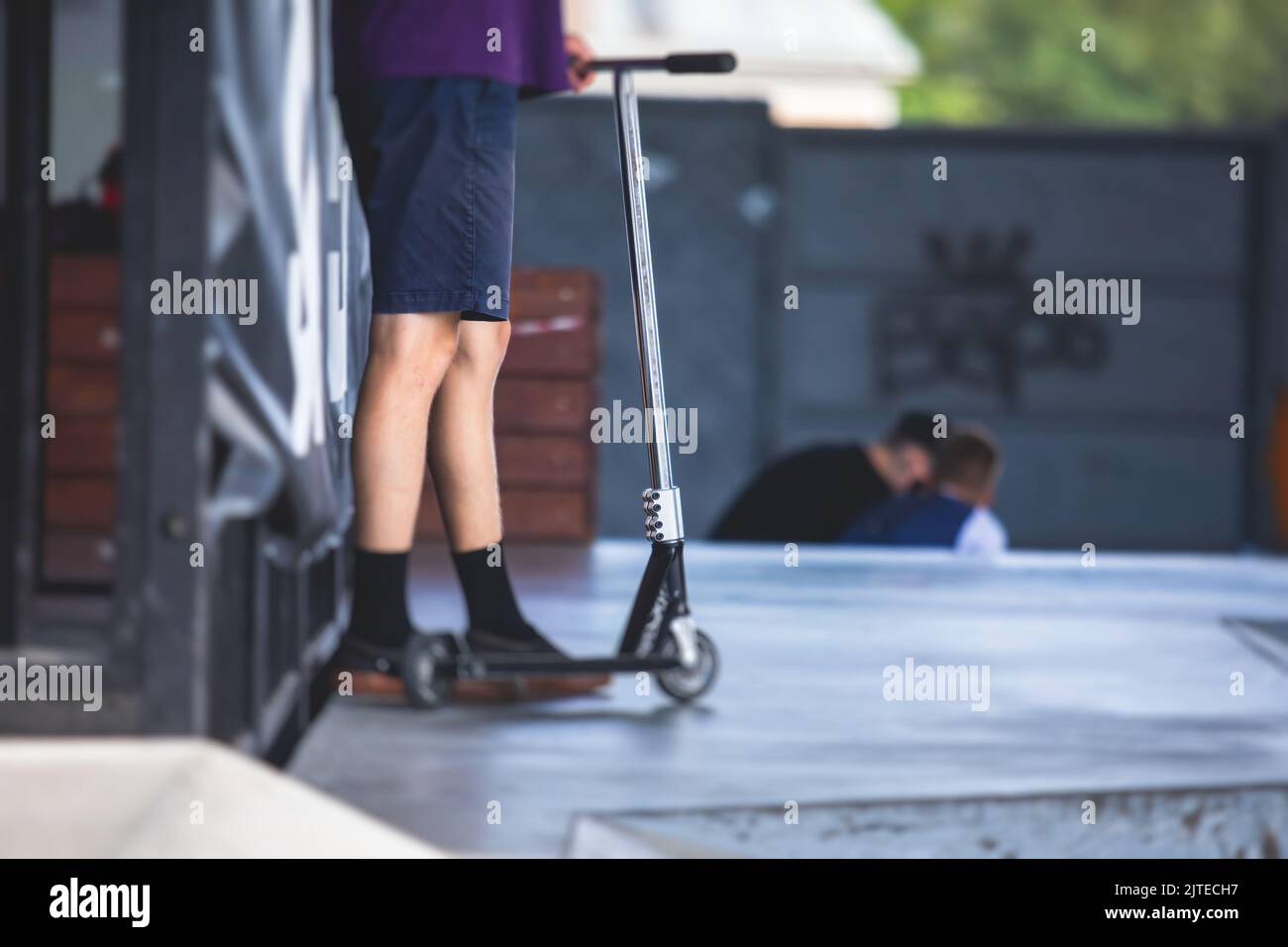 Skate park view with kids on a kick scooter doing tricks and stunts ...