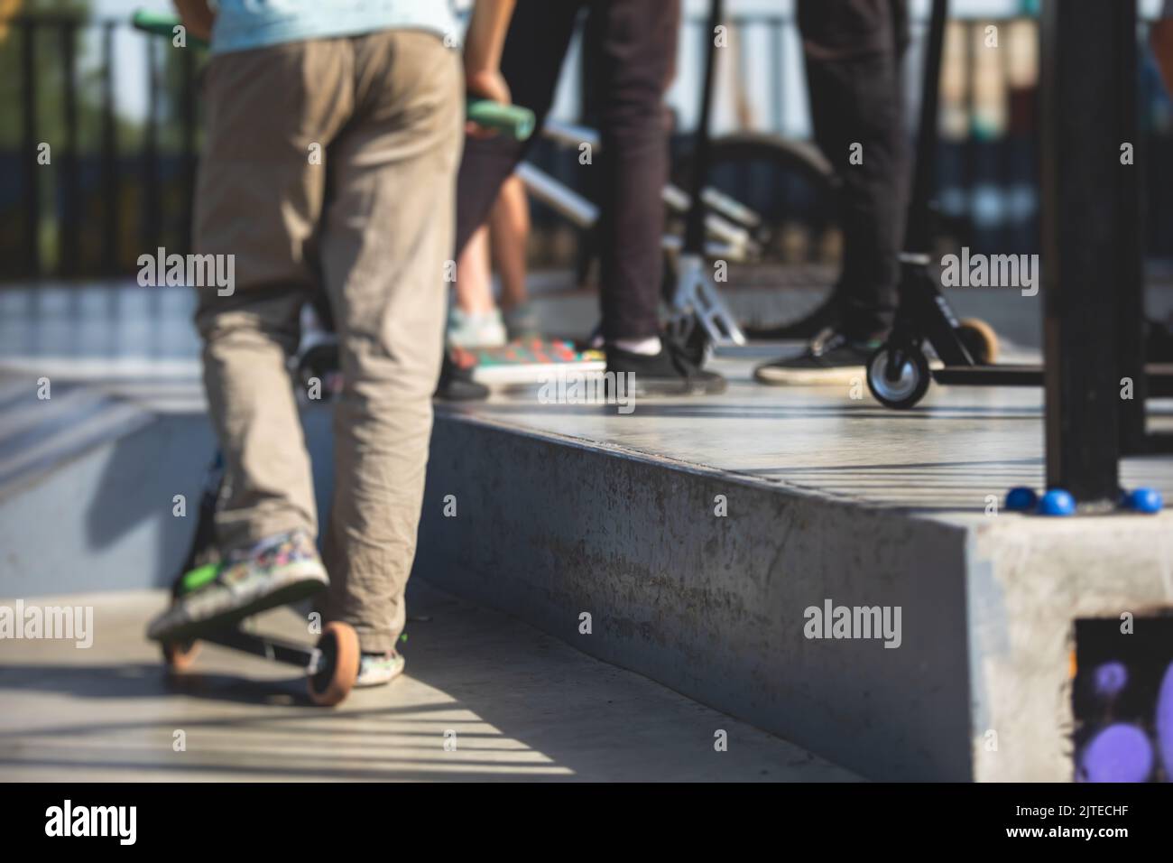 Skate park view with kids on a kick scooter doing tricks and stunts ...