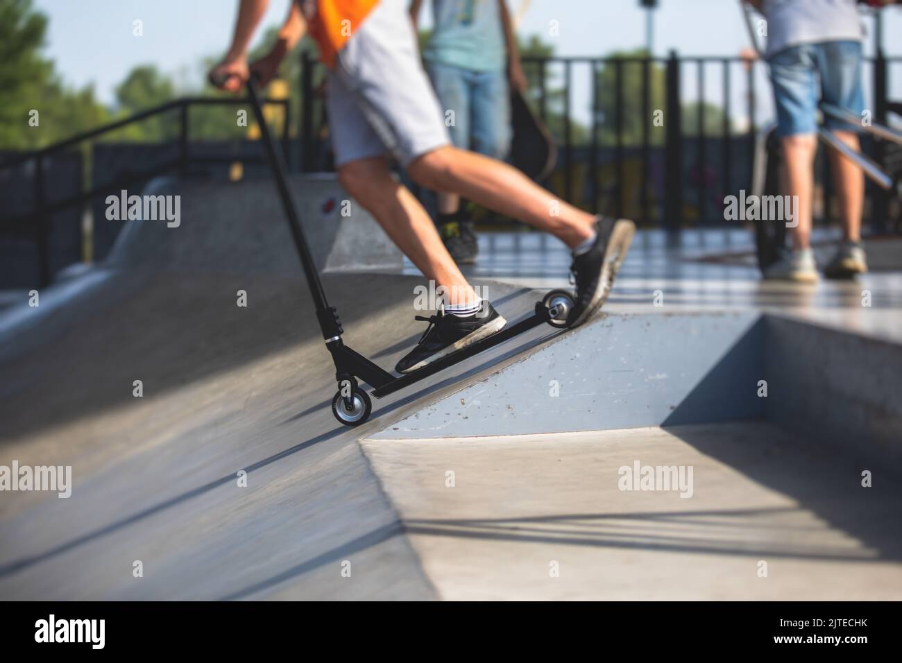 Skate park view with kids on a kick scooter doing tricks and stunts ...