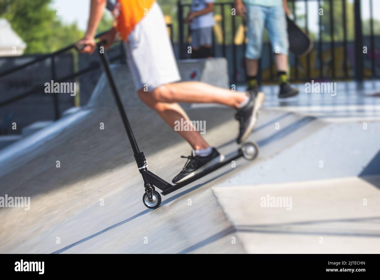 Skate park view with kids on a kick scooter doing tricks and stunts ...