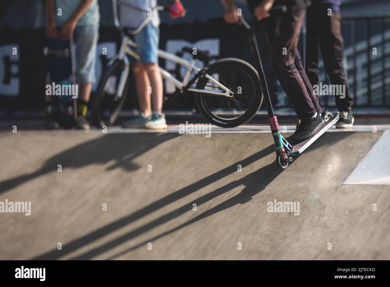 Skate park view with kids on a kick scooter doing tricks and stunts ...