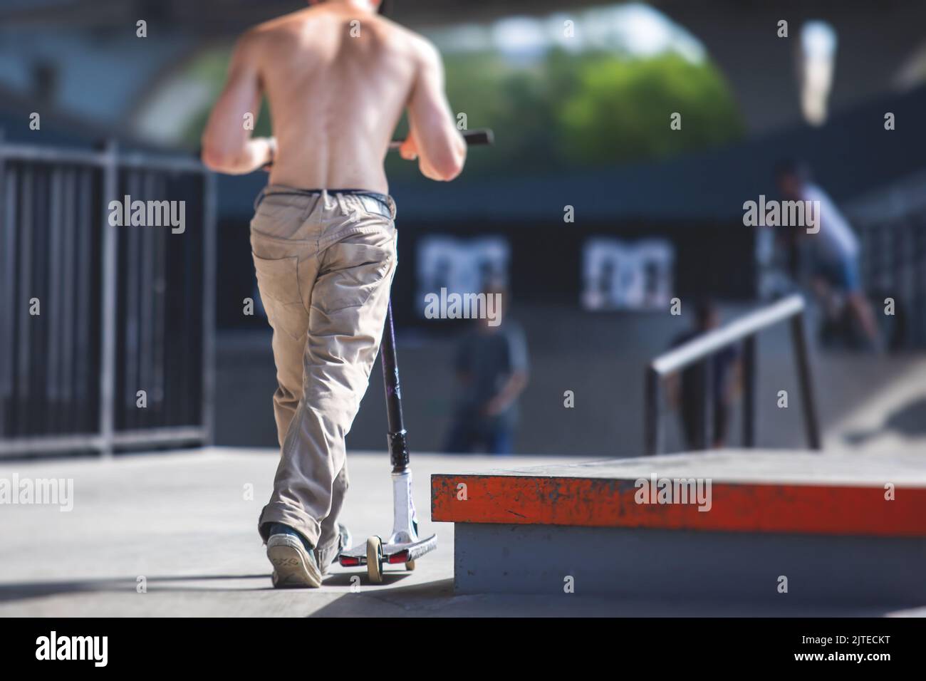 Skate park view with kids on a kick scooter doing tricks and stunts ...