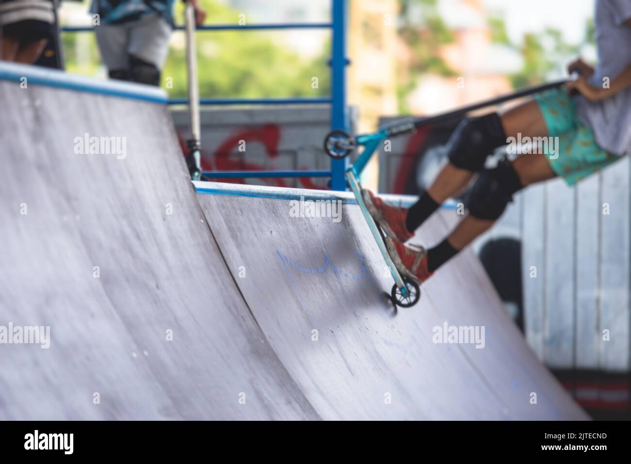 Skate park view with kids on a kick scooter doing tricks and stunts ...