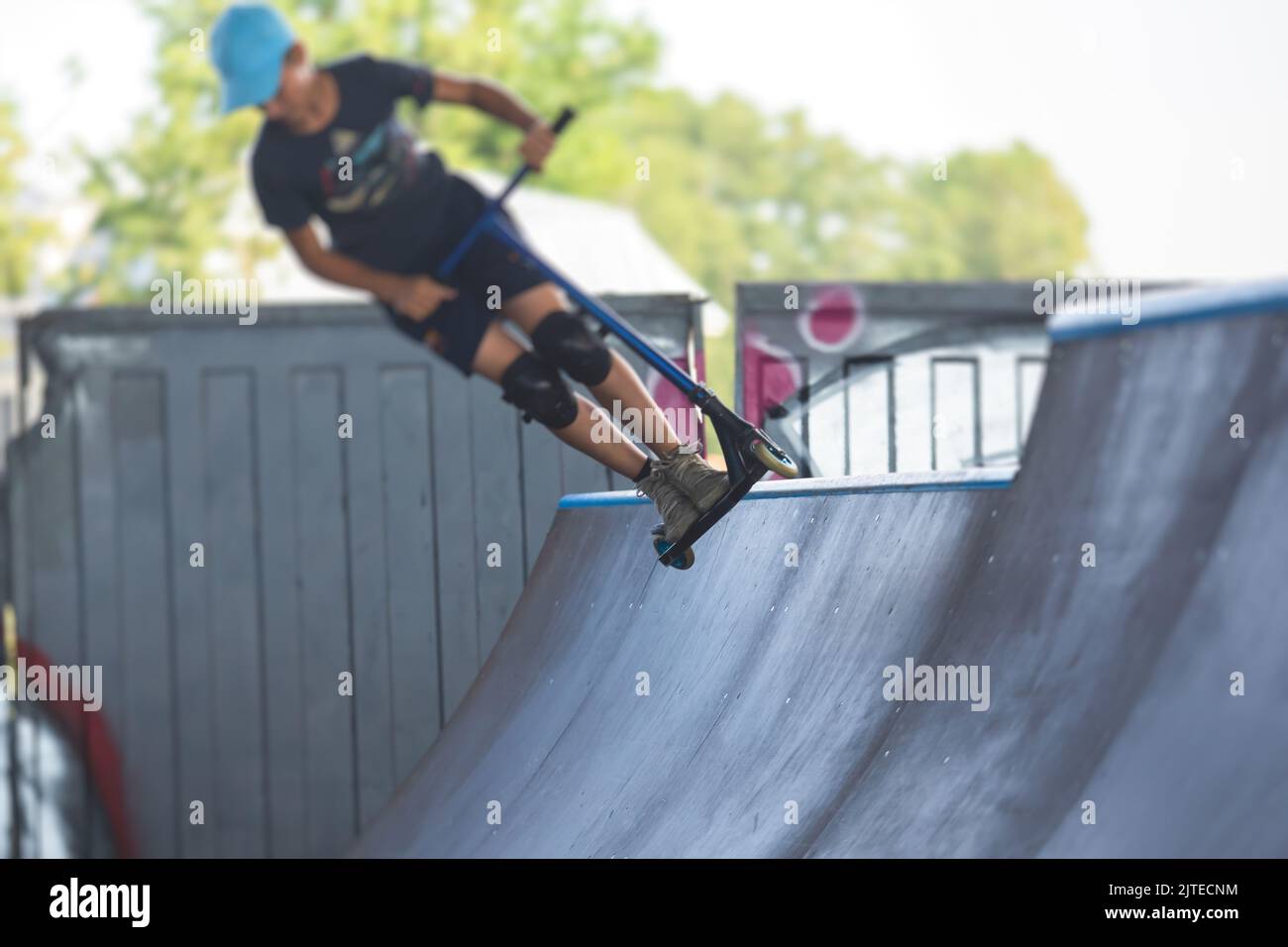 Skate park view with kids on a kick scooter doing tricks and stunts ...