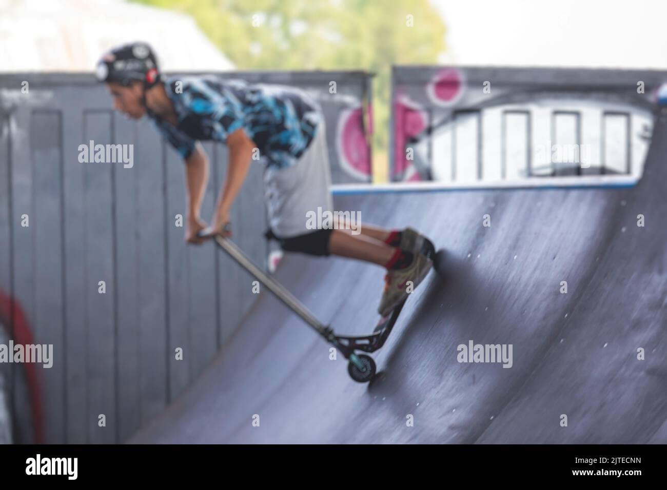 Skate park view with kids on a kick scooter doing tricks and stunts ...