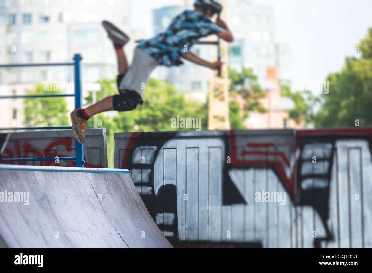 Skate park view with kids on a kick scooter doing tricks and stunts ...