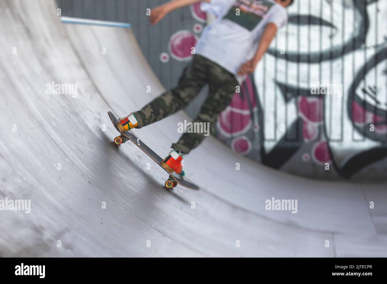 Skate park view with kids on a kick scooter doing tricks and stunts ...