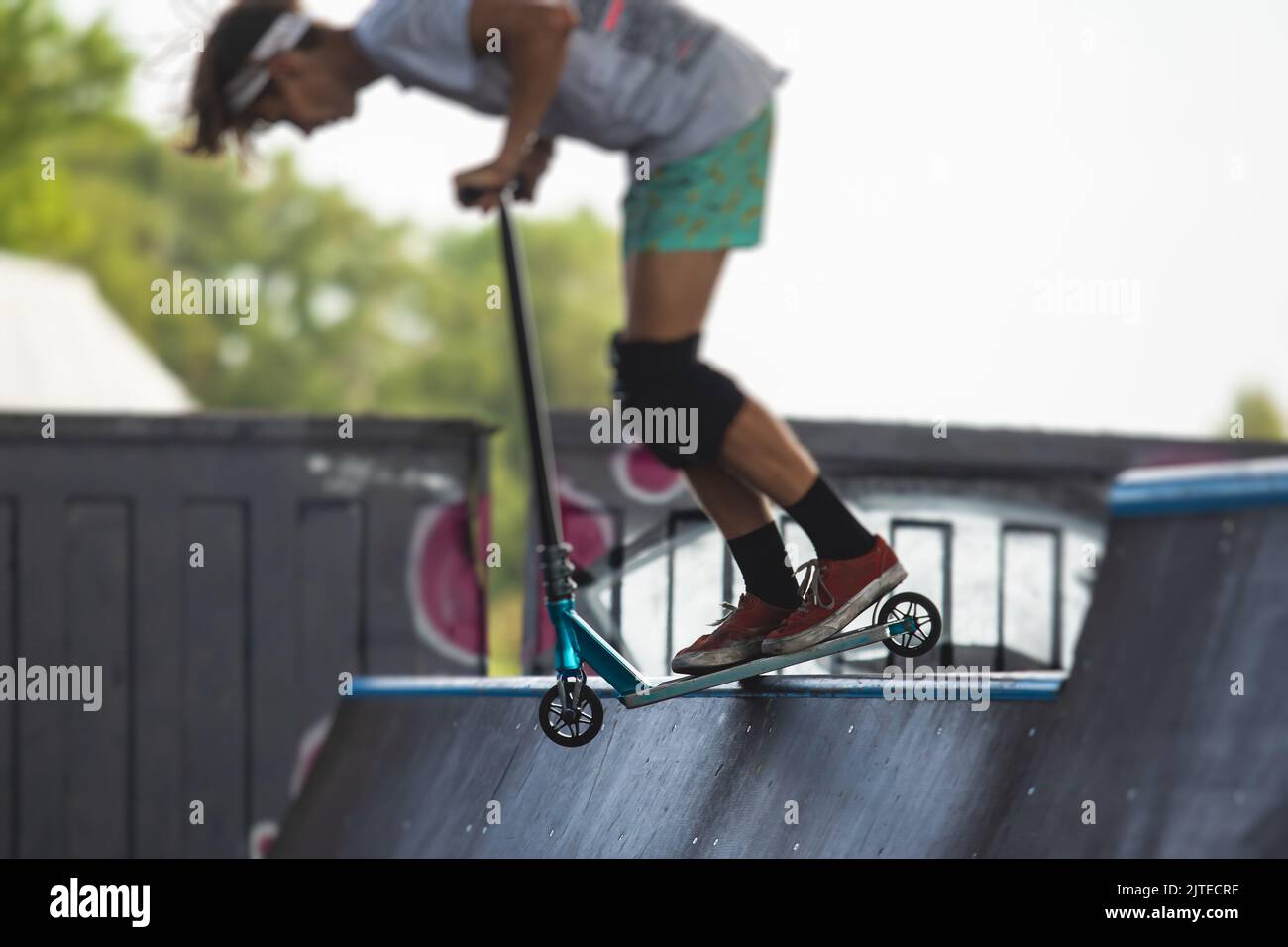 Skate park view with kids on a kick scooter doing tricks and stunts ...
