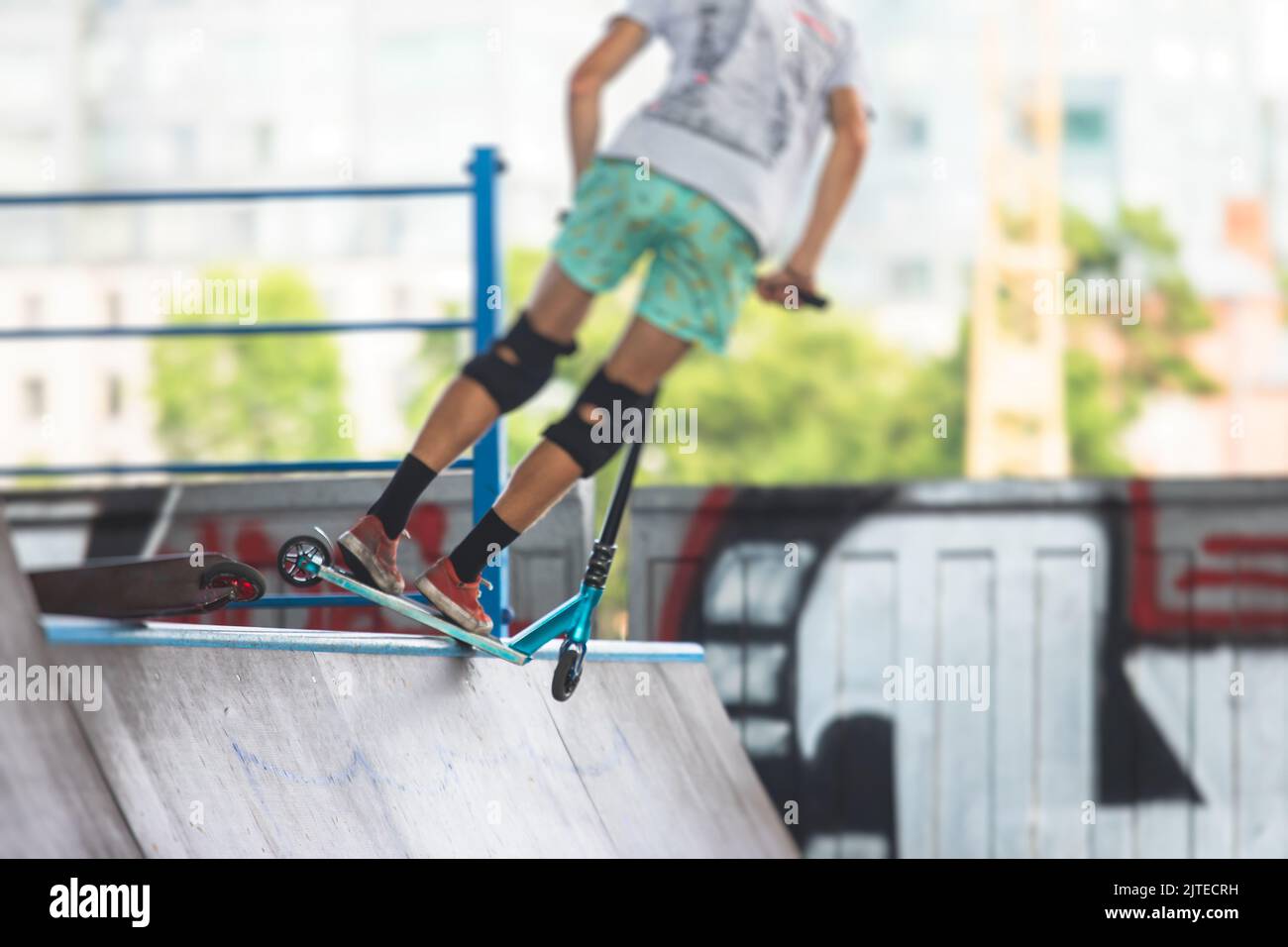 Skate park view with kids on a kick scooter doing tricks and stunts ...
