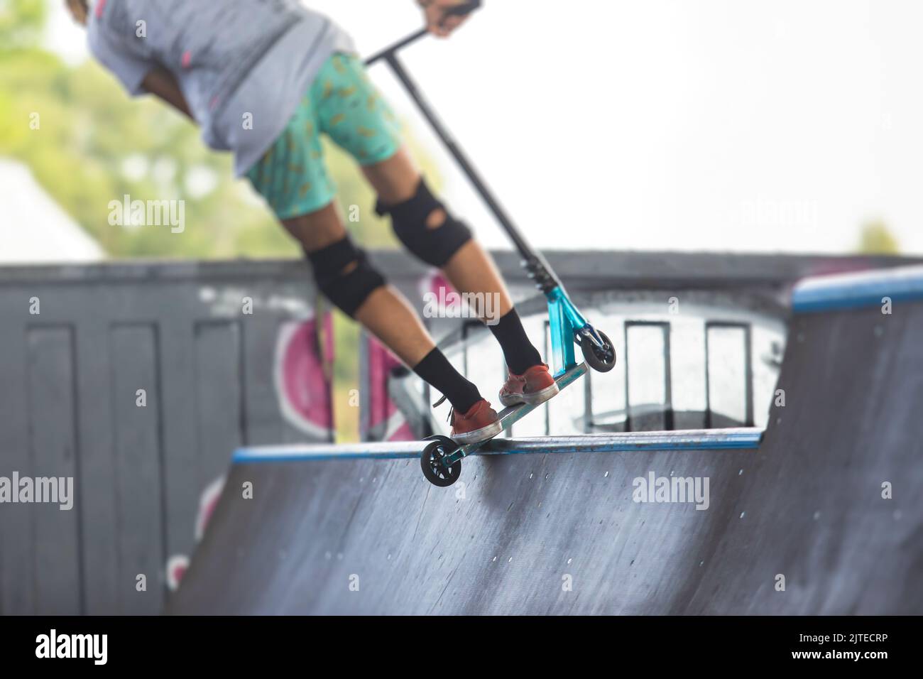 Skate park view with kids on a kick scooter doing tricks and stunts ...