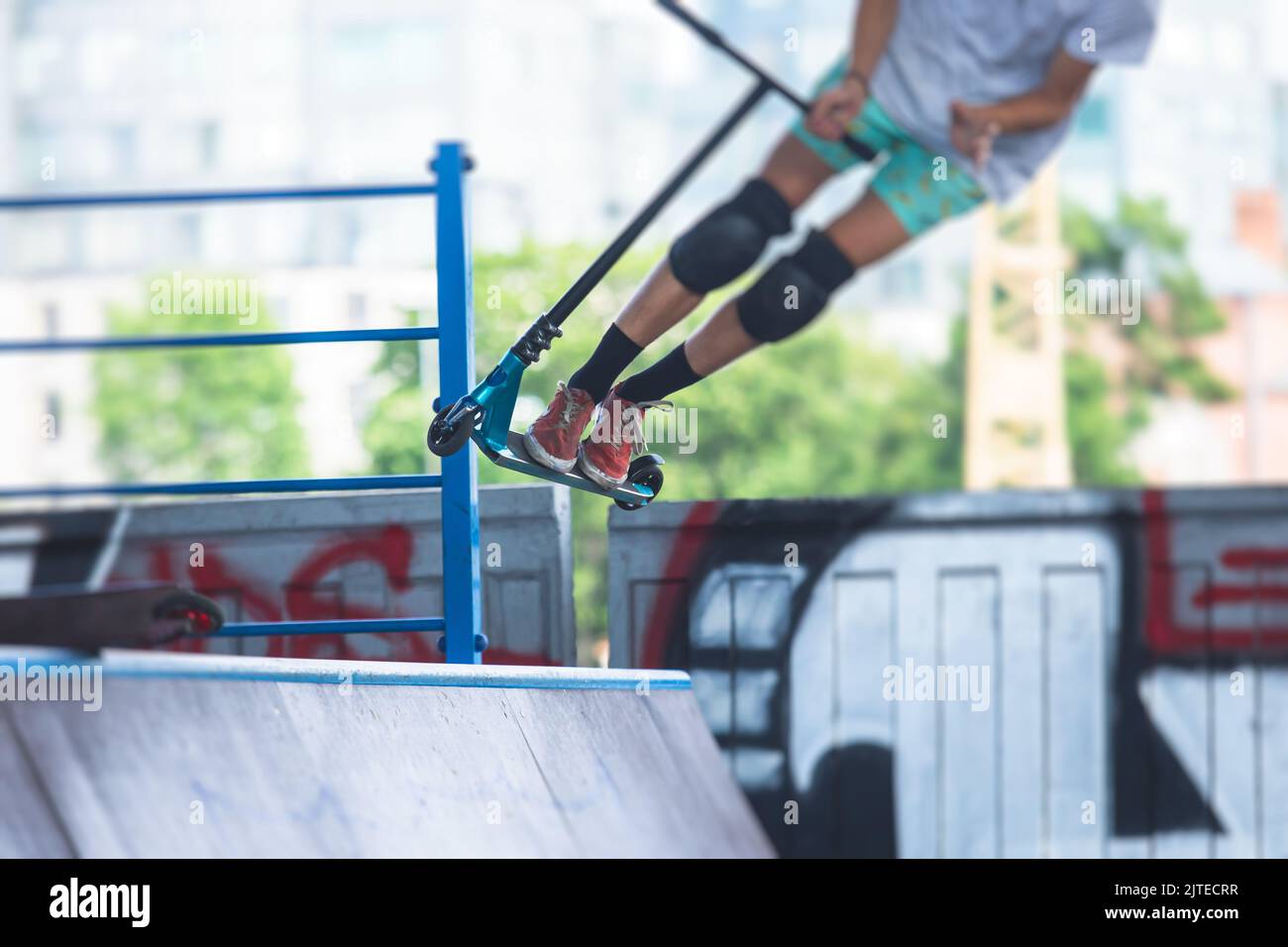 Skate park view with kids on a kick scooter doing tricks and stunts ...