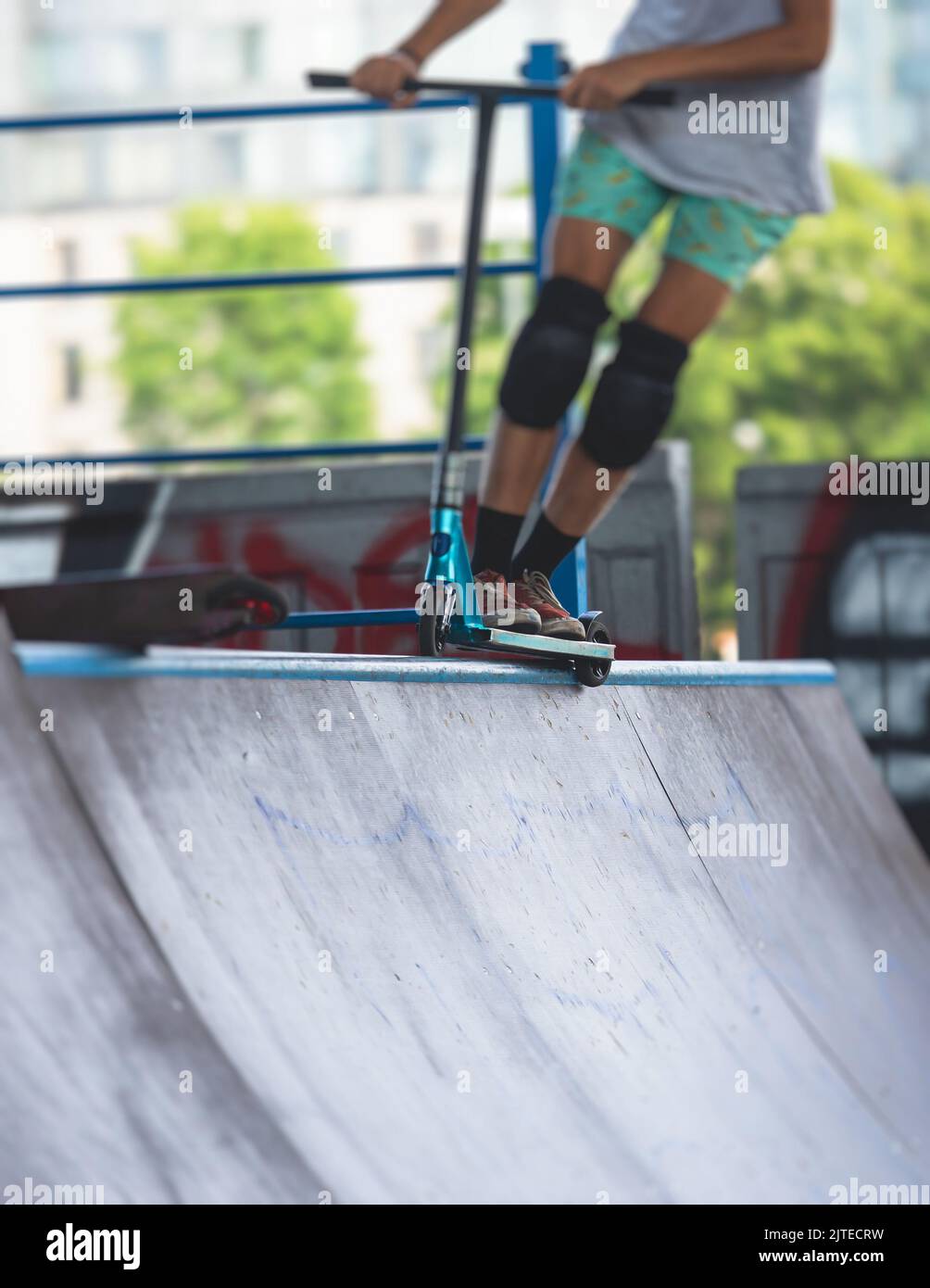 Skate park view with kids on a kick scooter doing tricks and stunts ...