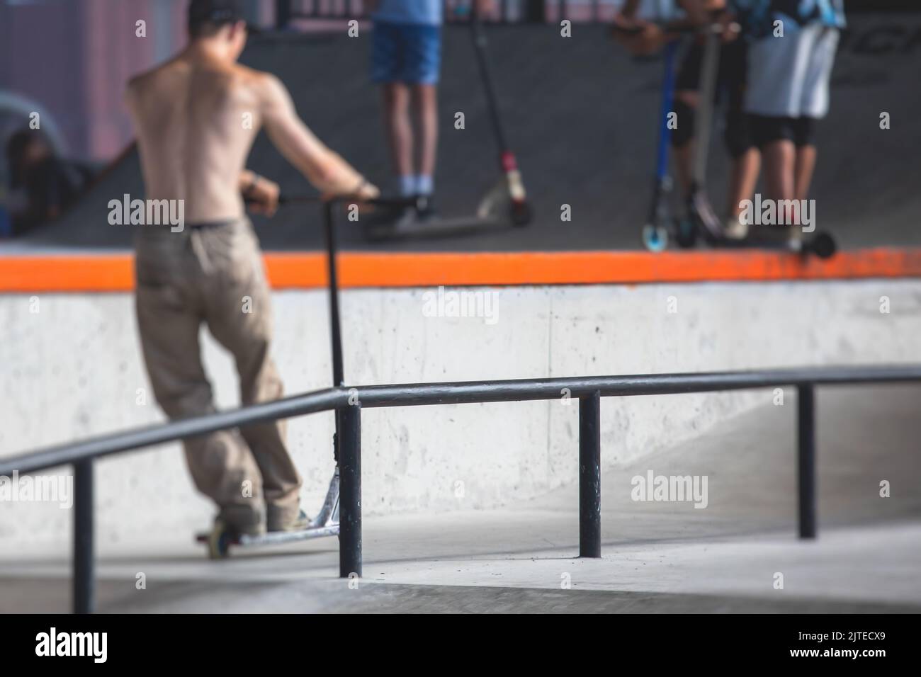 Skate park view with kids on a kick scooter doing tricks and stunts ...