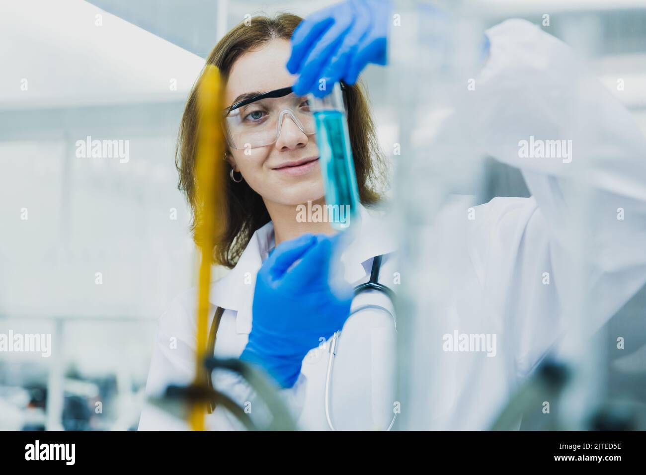 female researcher, medical scientist or doctor with test tube of clear ...