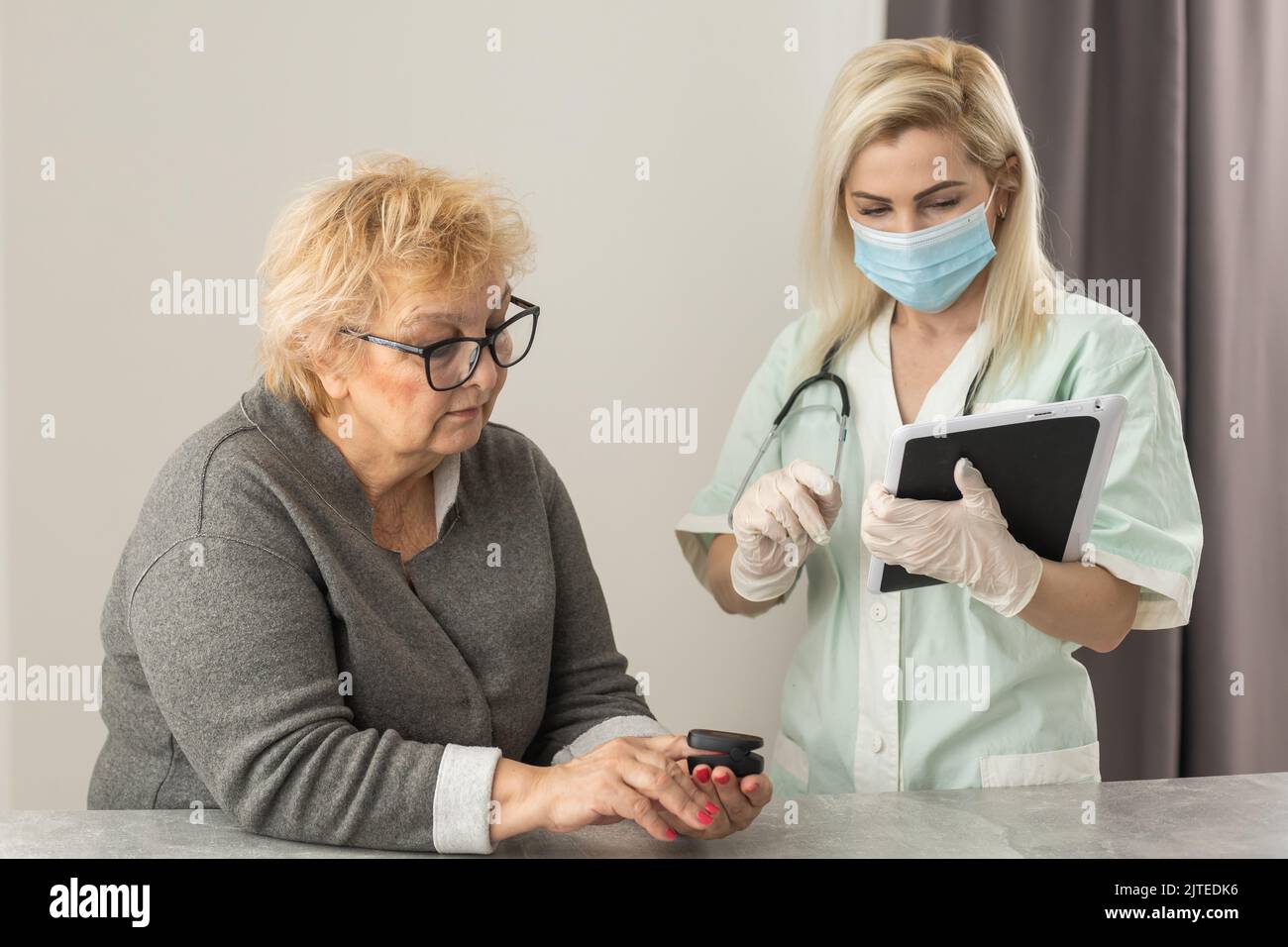 Hand of senior woman with an attached pulse oximeter on fingertip,old ...