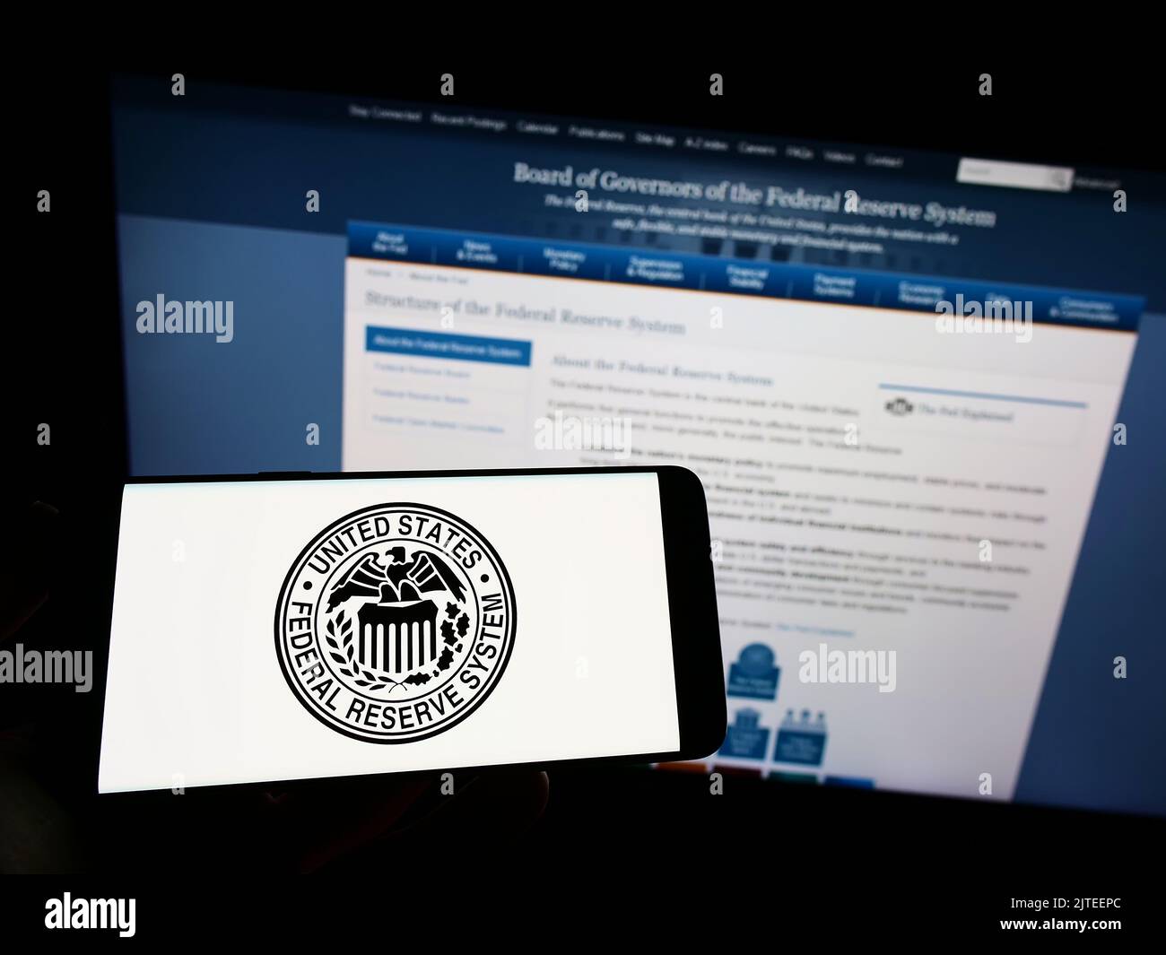 Person holding mobile phone with seal of United States Federal Reserve ...