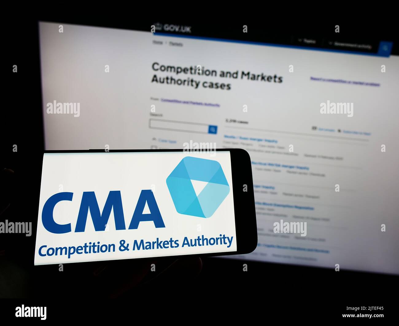 Person holding mobile phone with logo of British Competition and ...