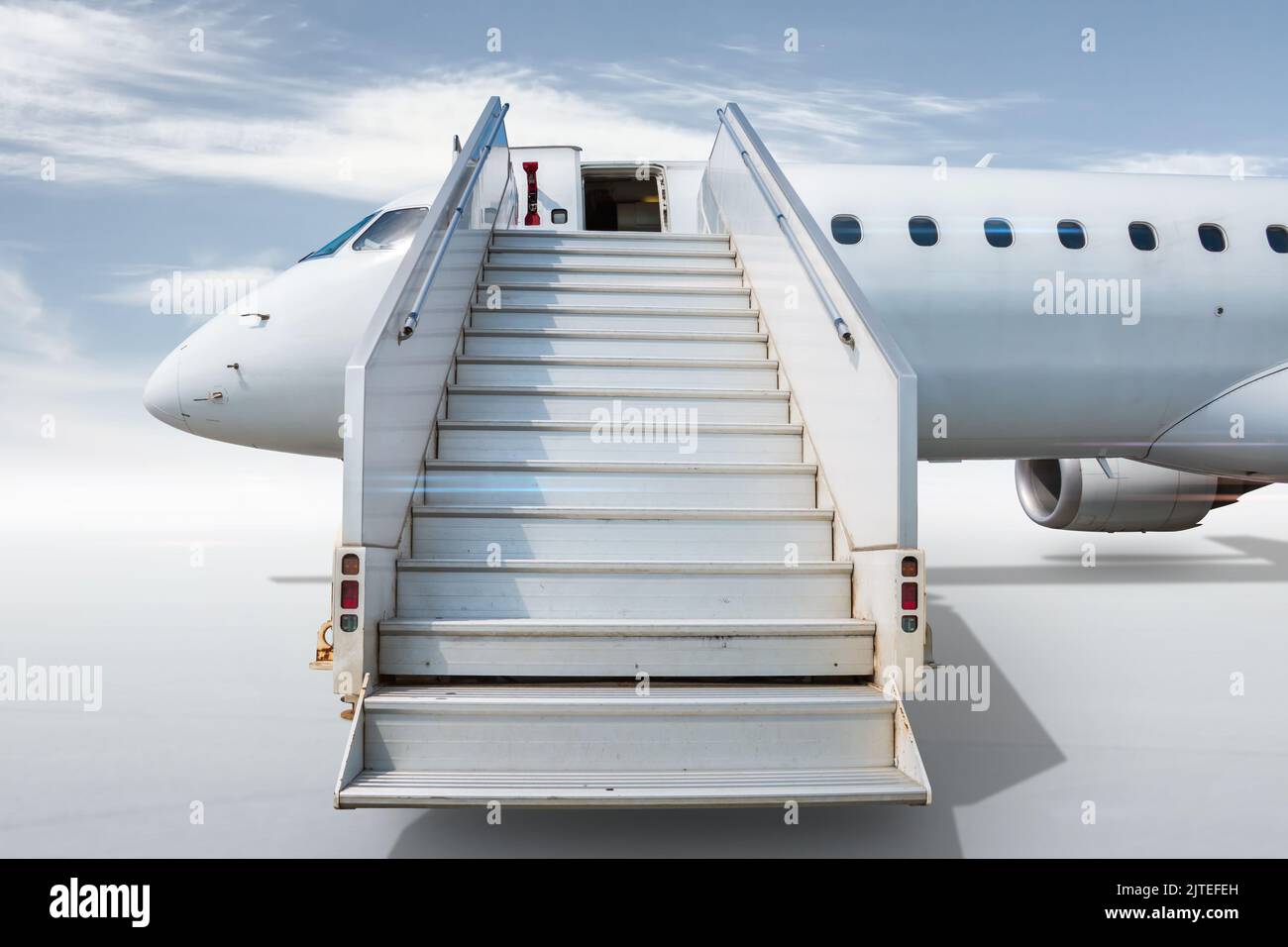 White passenger airliner with a stairway isolated on bright background ...