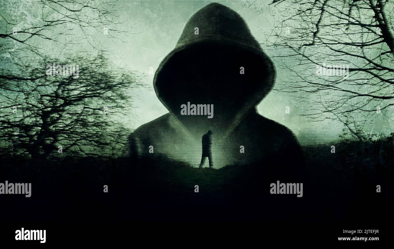 A spooky horror concept of a ghostly hooded figure silhouetted against ...