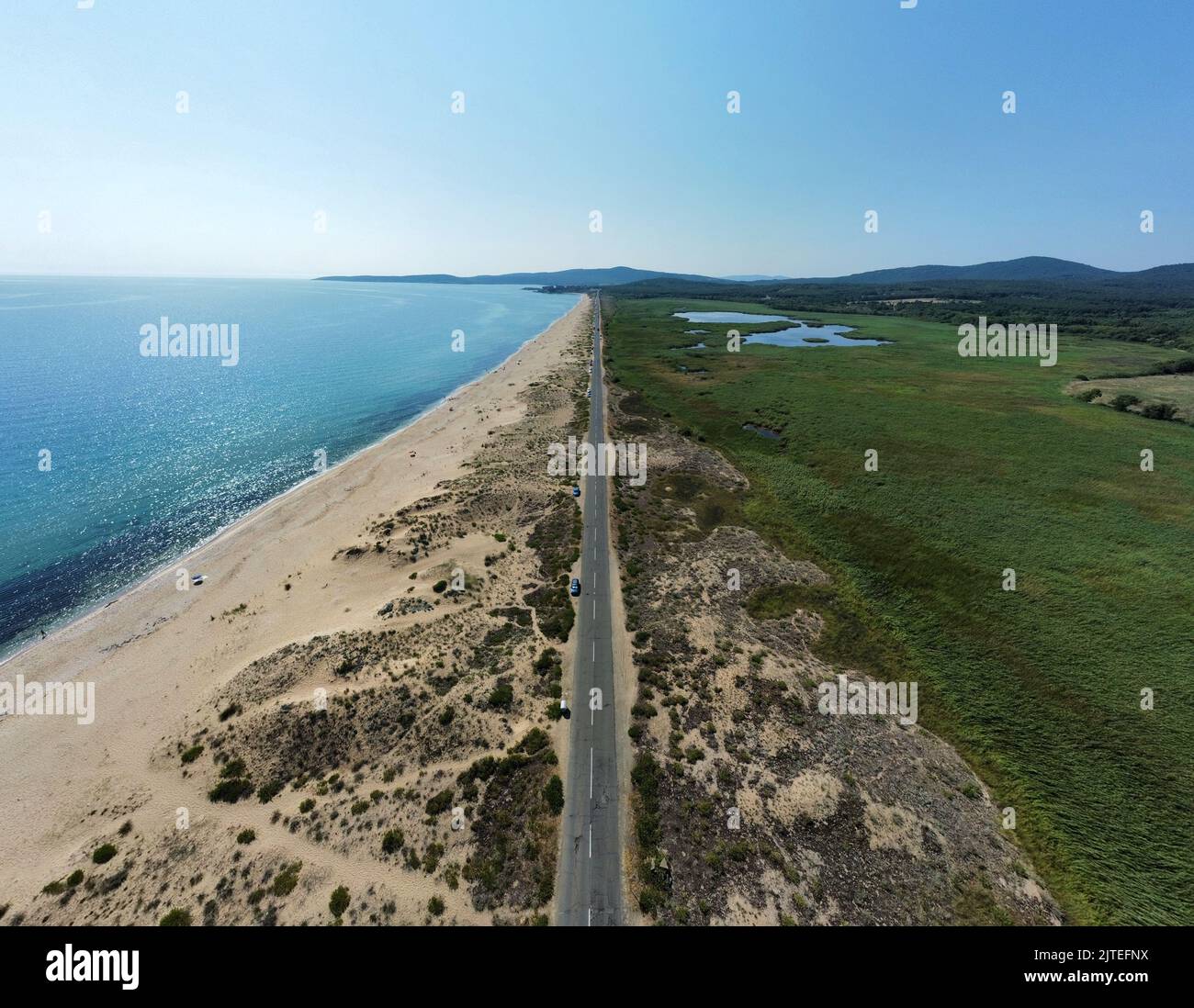 An aerial view of a road between green hill and sandy beach Stock Photo ...
