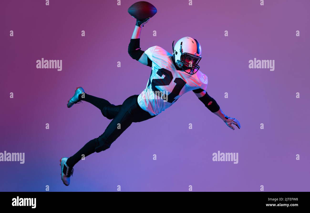 Portrait of american football player in motion, catching ball in a jump ...