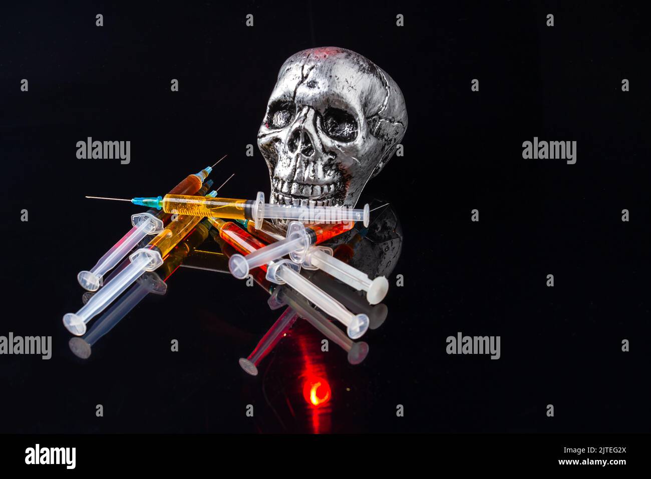 Close-up iron skull with syringes isolated on black background. Pile of ...