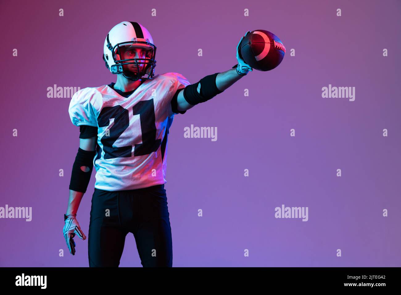 Portrait of young man, american football player in uniform training ...